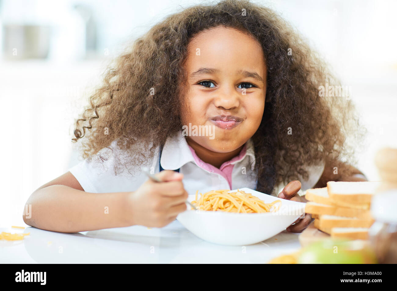 Cute girl eating pasta and looking at camera Stock Photo - Alamy