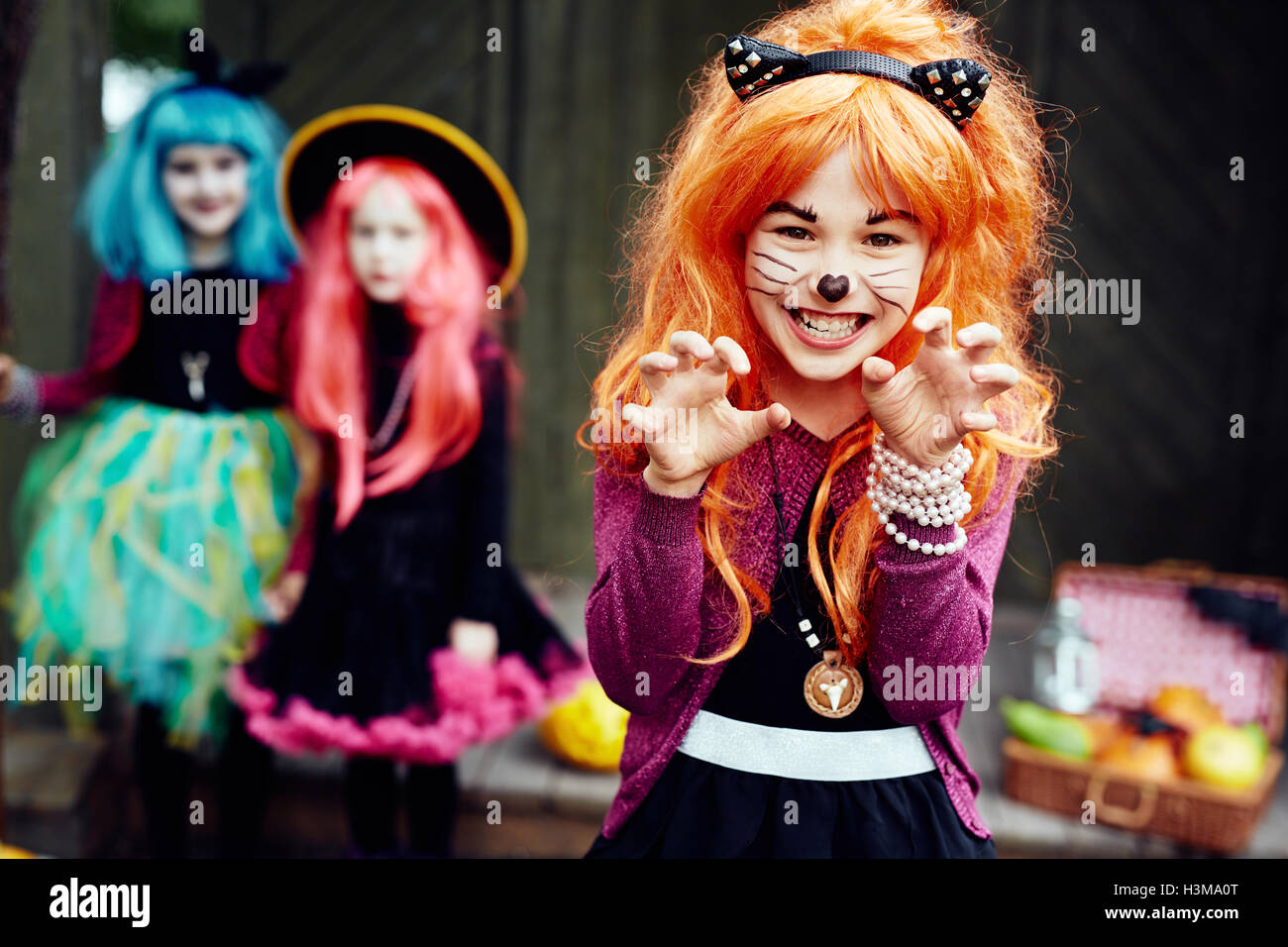 Girl with painted face and wig looking at camera with frightening ...