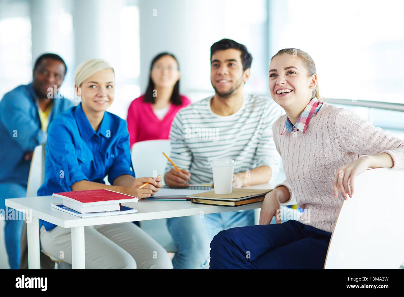 Young students listening to teacher at lesson Stock Photo - Alamy