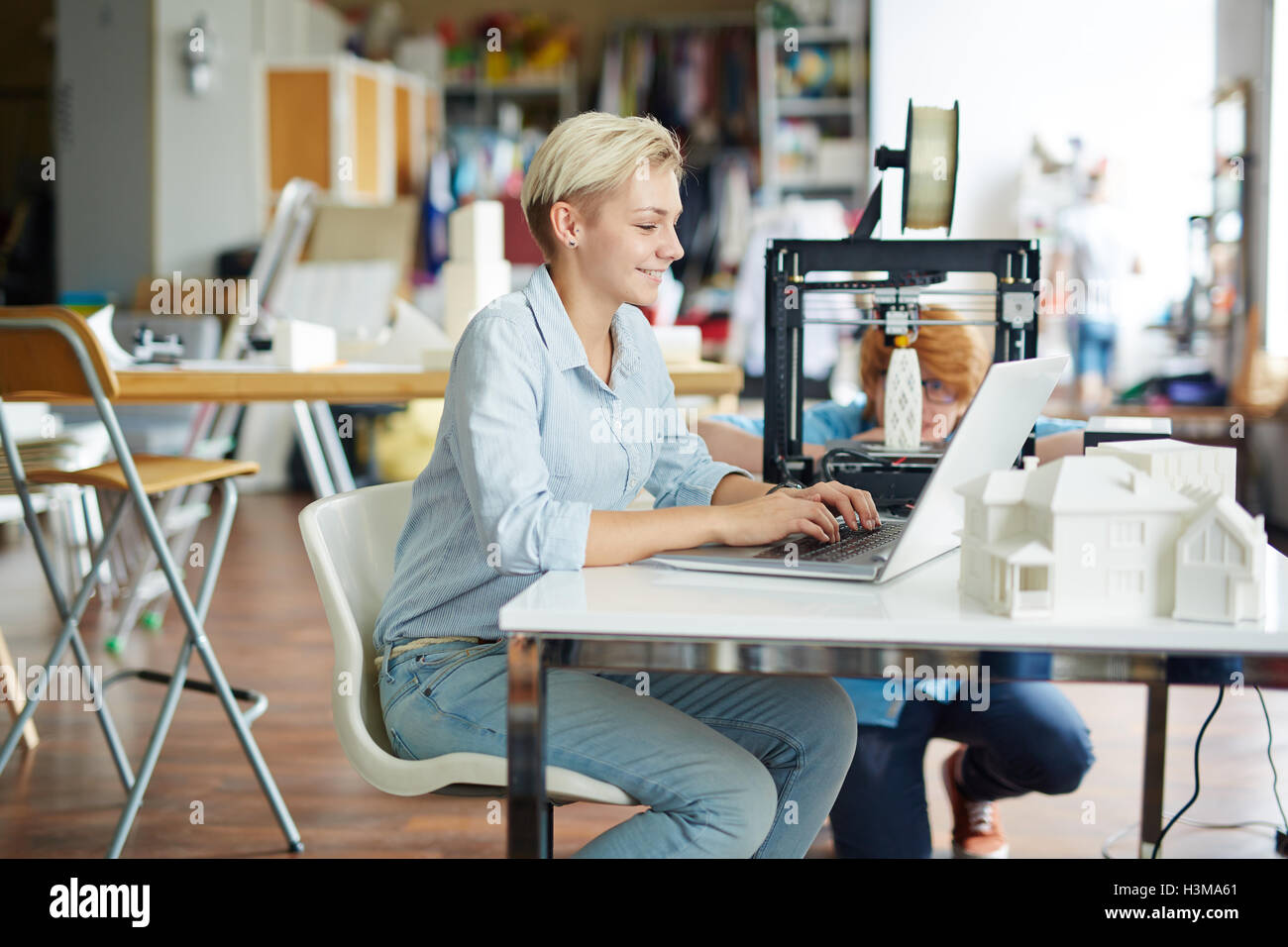 Young woman typing at workplace while male colleague looking at ...