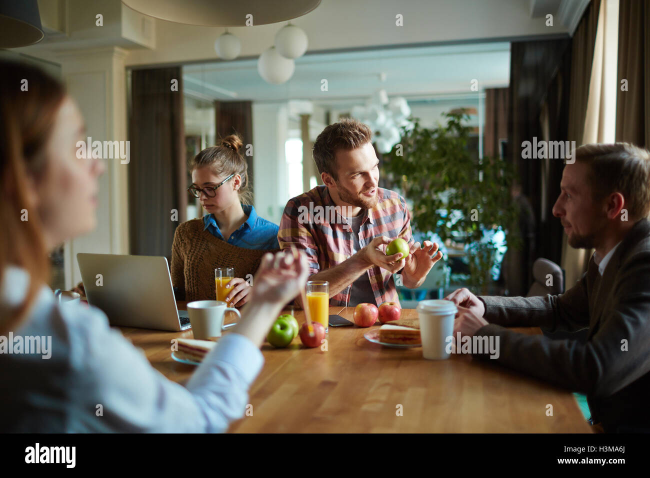 Young employee talking to his colleague during lunch break in office ...