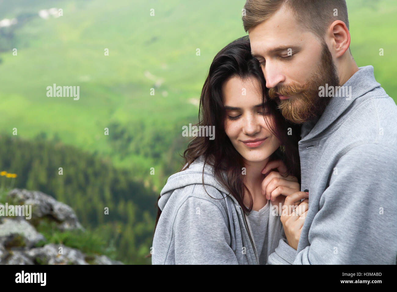 Young loving couple relaxing and hugging, she is smiling and leaning on ...