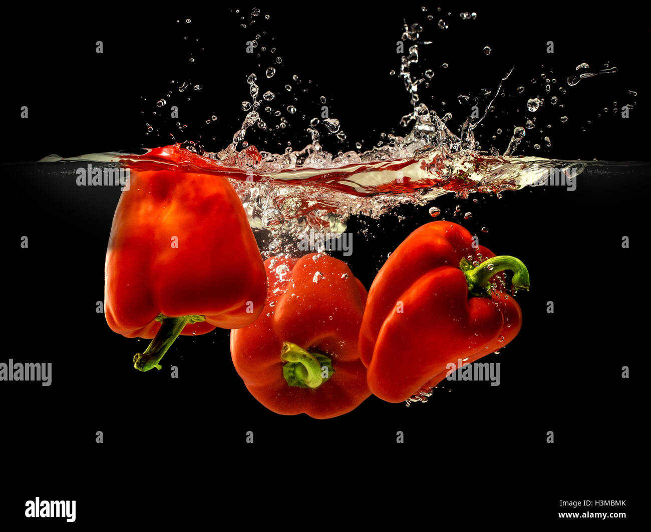 Group of bell pepper falling in water on black Stock Photo - Alamy
