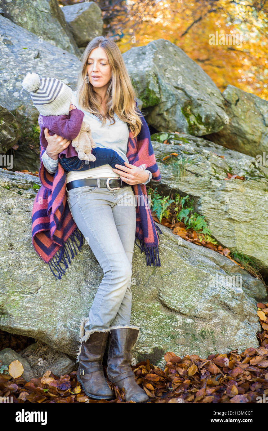 Mother leaning against rocks holding baby girl Stock Photo - Alamy