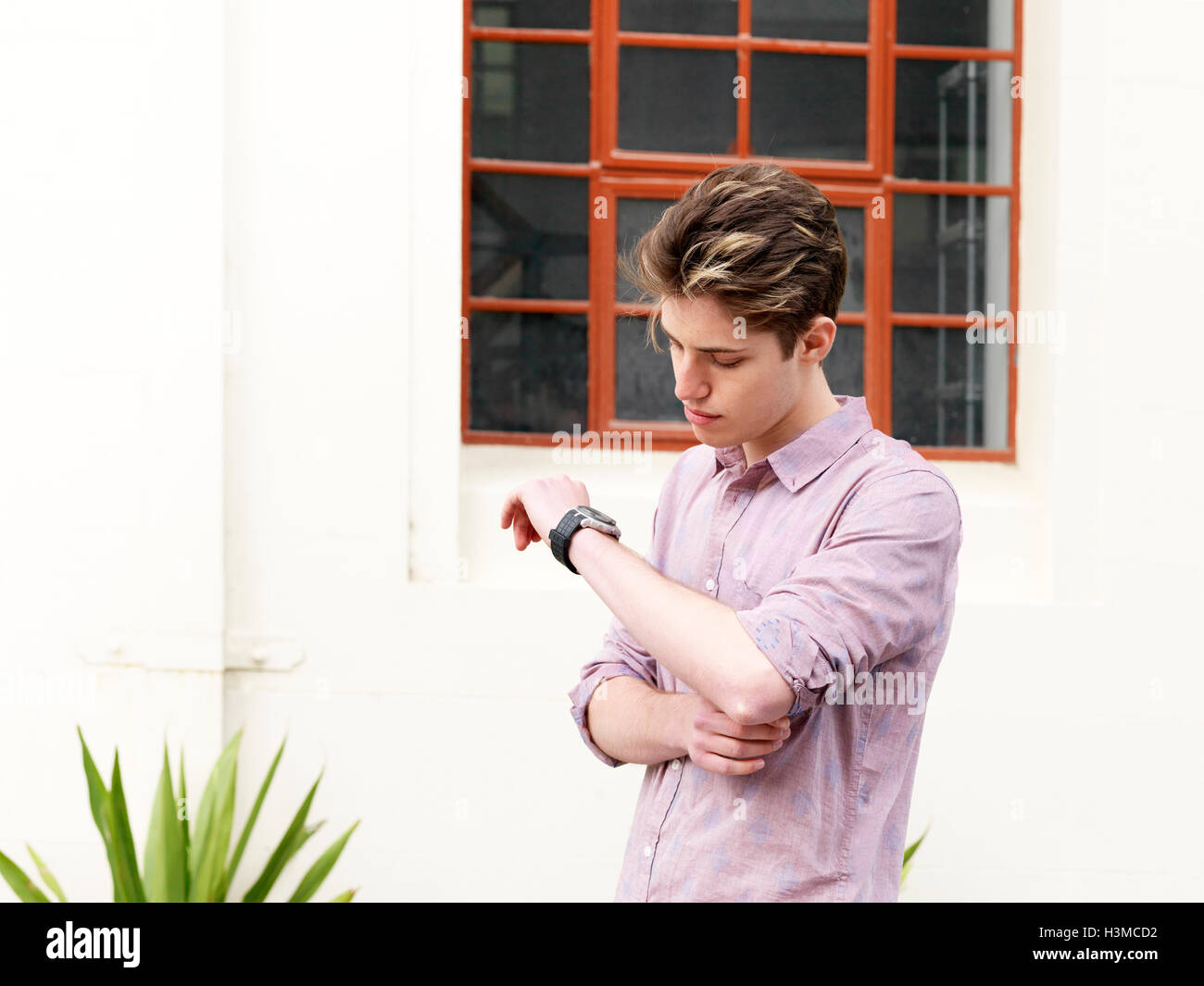 Young man looking at watch, outdoors Stock Photo - Alamy