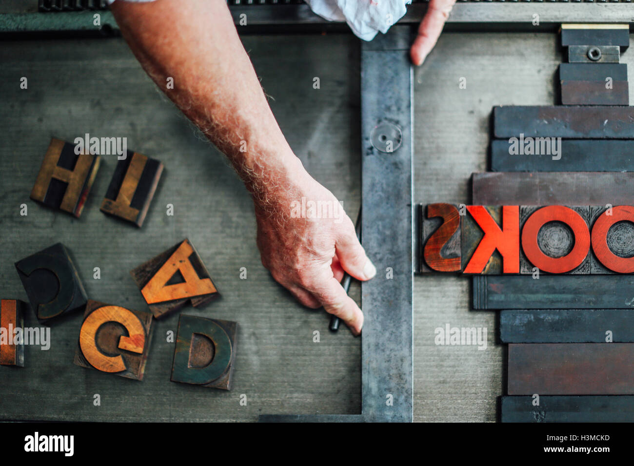 Detail of hand using letterpress machine in book arts workshop ...
