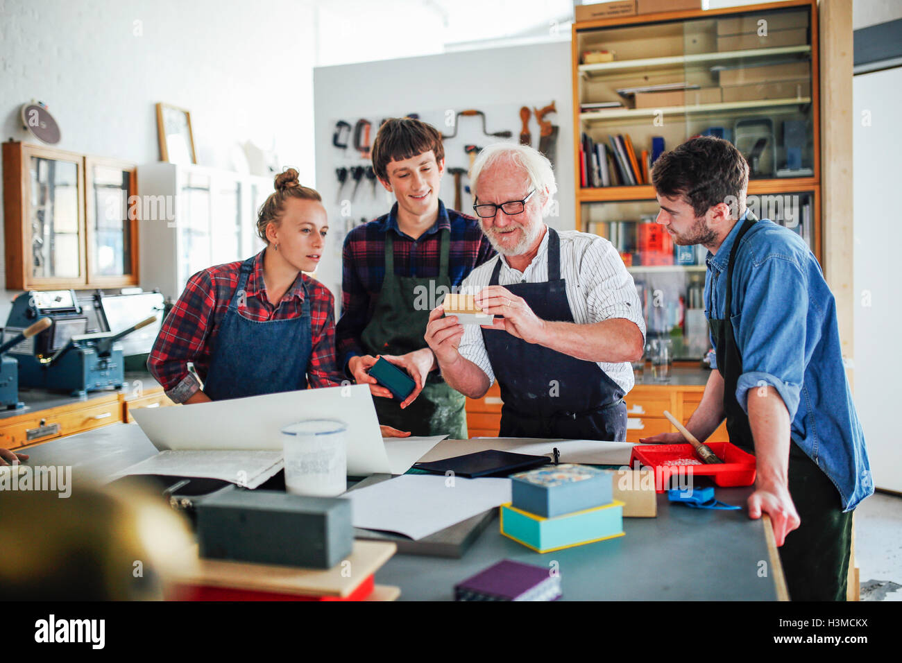 Senior male workshop leader showing materials to young group of men and ...