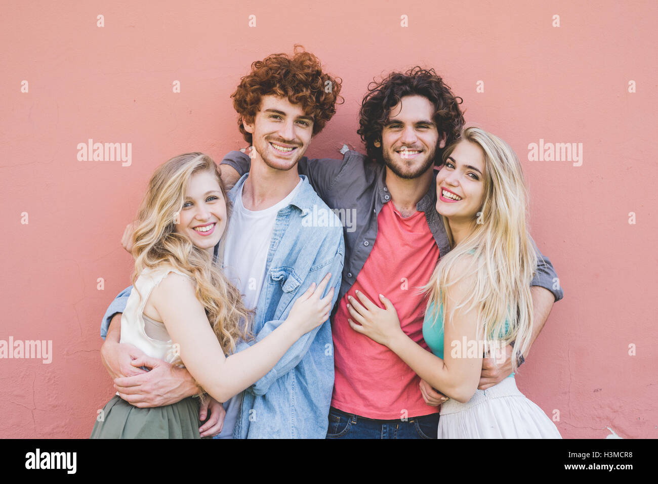 Couples hugging against pink wall background Stock Photo - Alamy