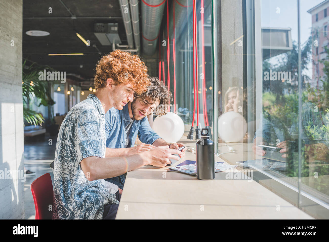 Co-workers working on laptop beside bar counter by window Stock Photo ...