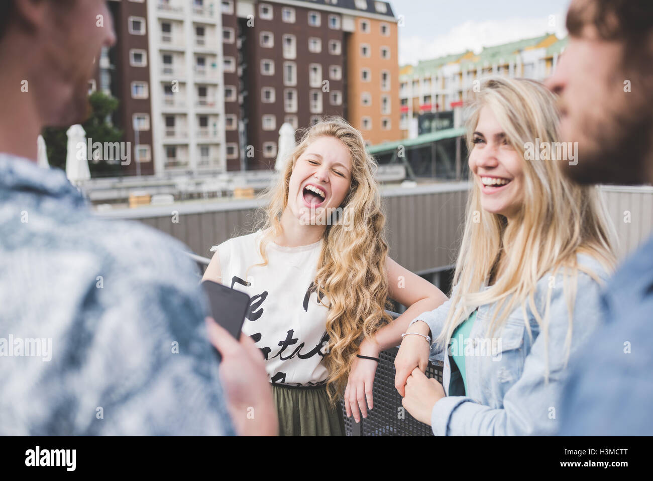 Friends standing and chatting beside rail Stock Photo - Alamy