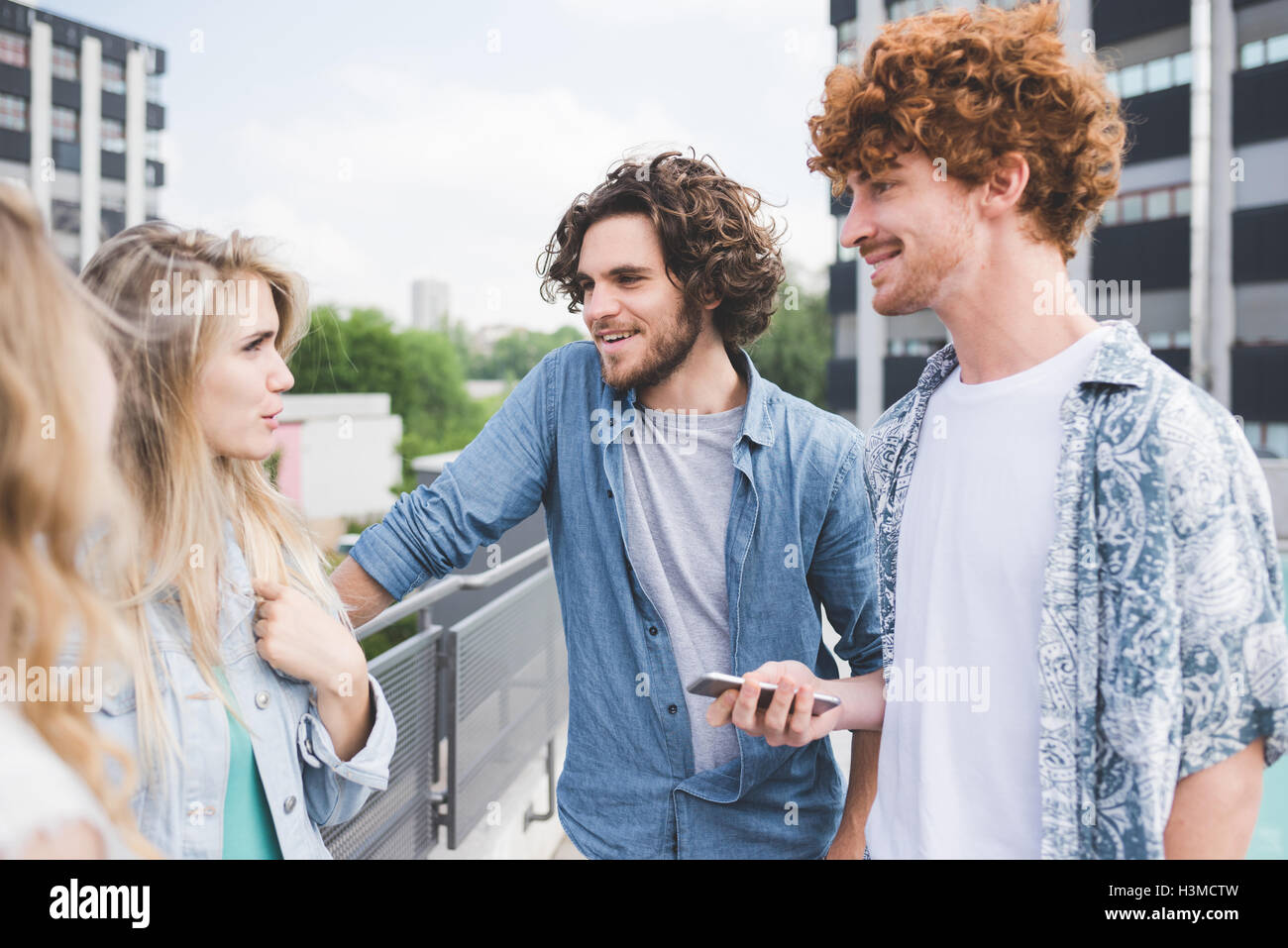 Friends standing and chatting beside rail Stock Photo - Alamy