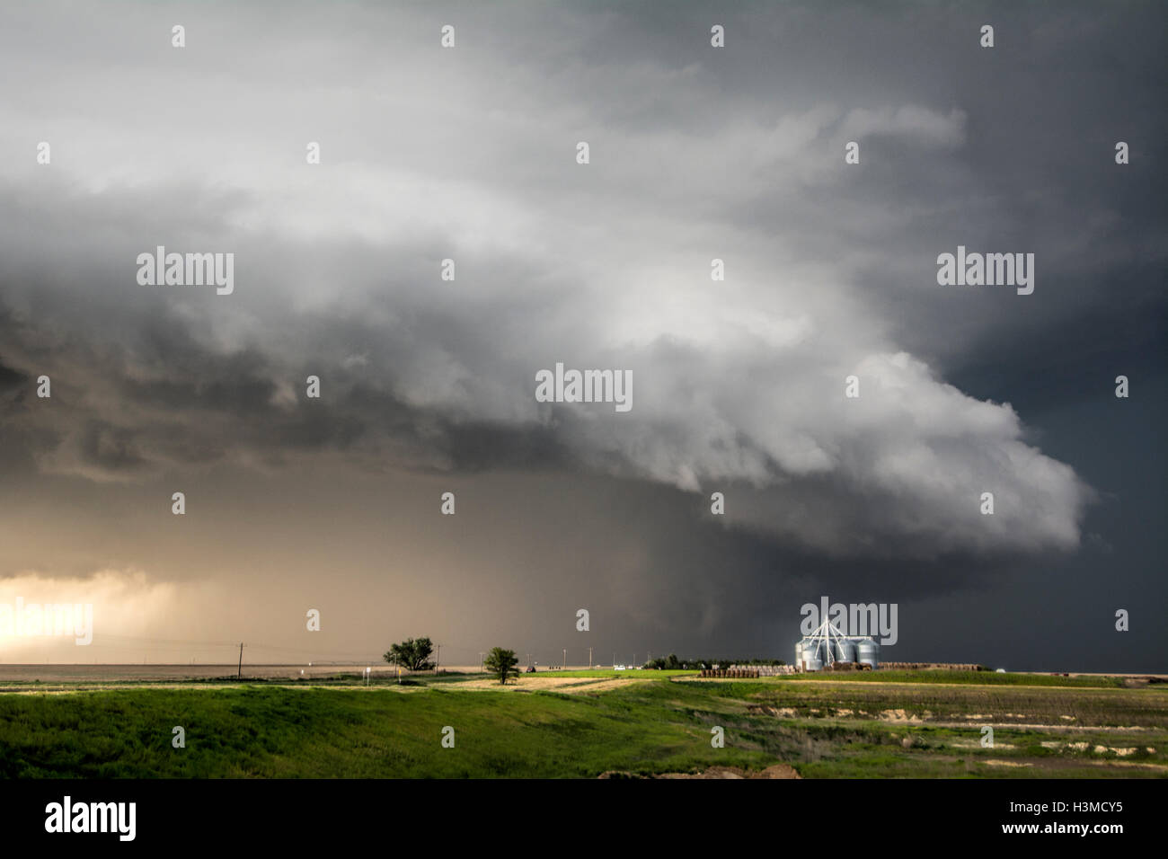 A tornado-producing supercell thunderstorm spinning over ranch land ...
