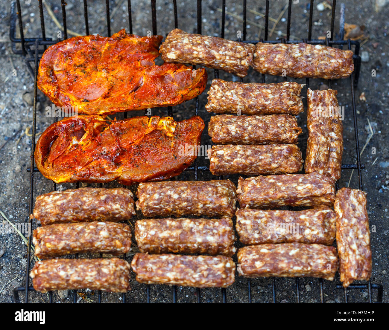 Minced meat rolls and pork steak on the grill outdoor, cooking Stock ...