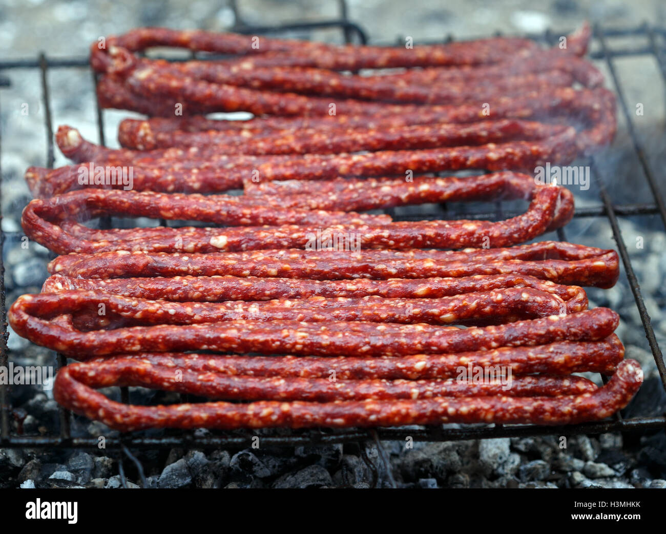 Stick sausages cooking on a grill outdoor with embers Stock Photo - Alamy