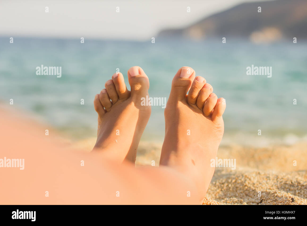 Woman legs on the sandy beach over sea in background Stock Photo - Alamy