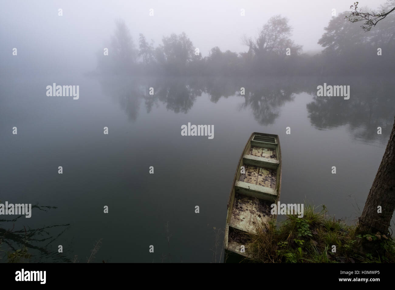 An empty boat moored at river bank on a foggy morning Stock Photo - Alamy