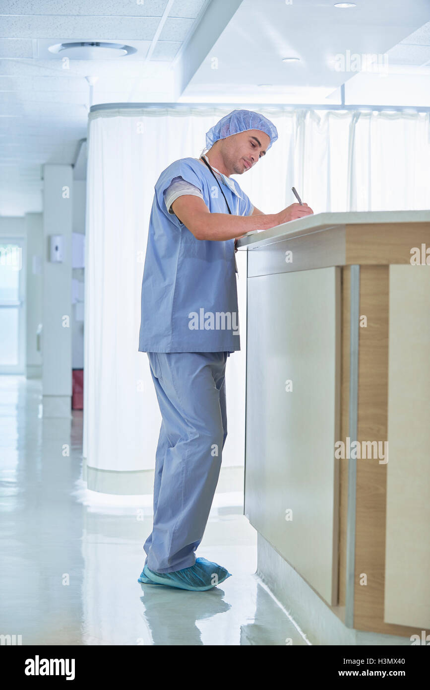 Doctor writing up medical notes at hospital nurses station Stock Photo ...
