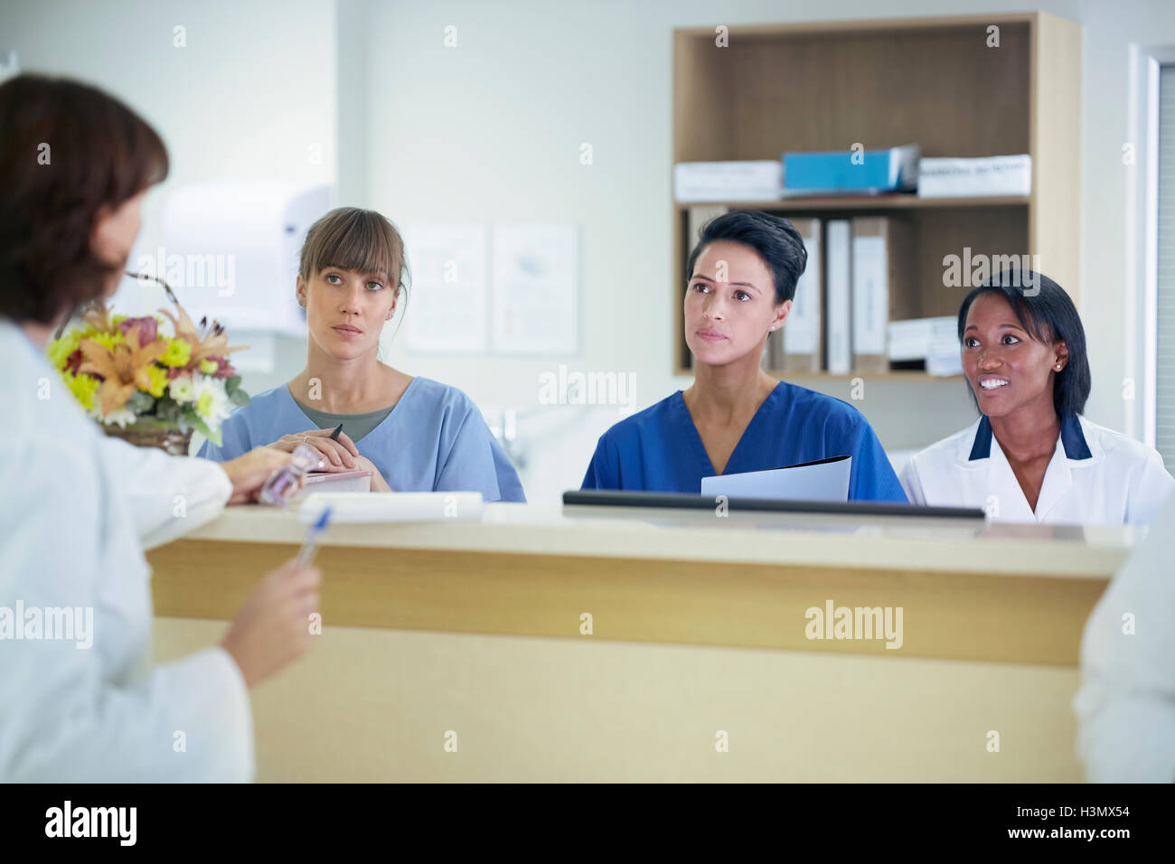 Female doctor having discussion with nurses at nurses station in ...