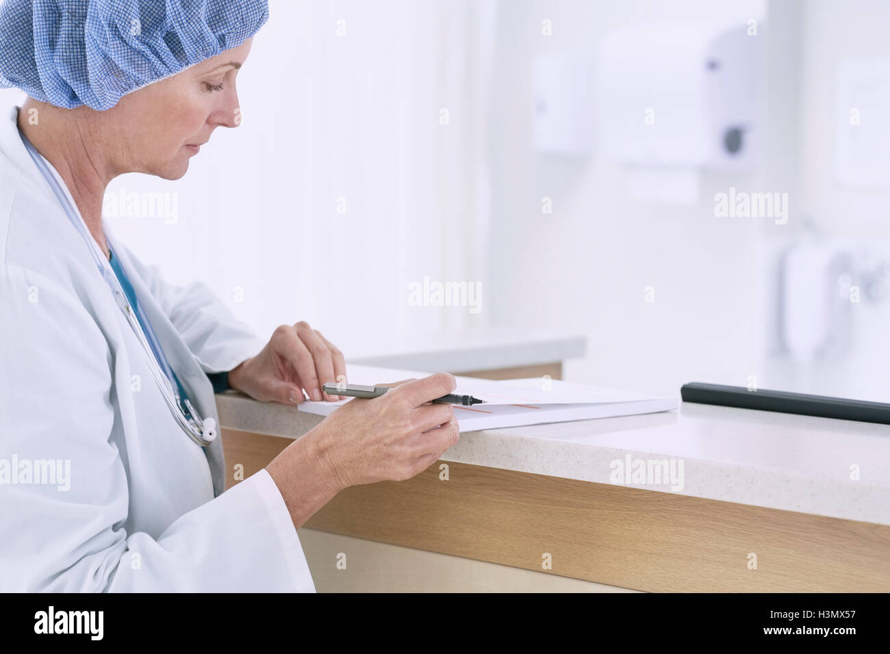 Female doctor writing medical notes at nurses station in hospital Stock ...