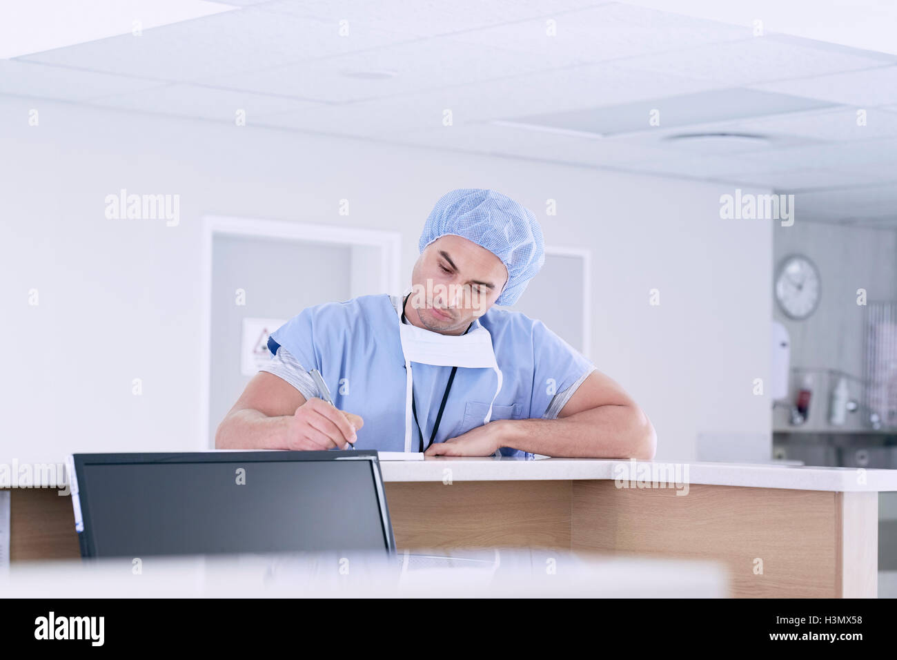Male doctor writing medical notes at nurses station in hospital Stock ...