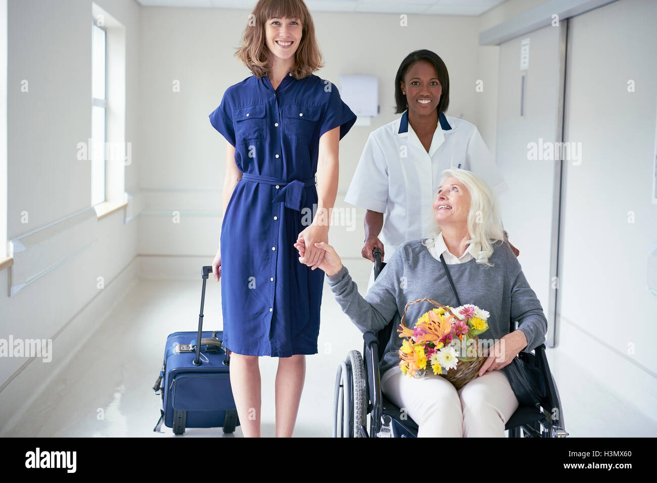 Daughter and hospital orderly pushing senior female patient in ...