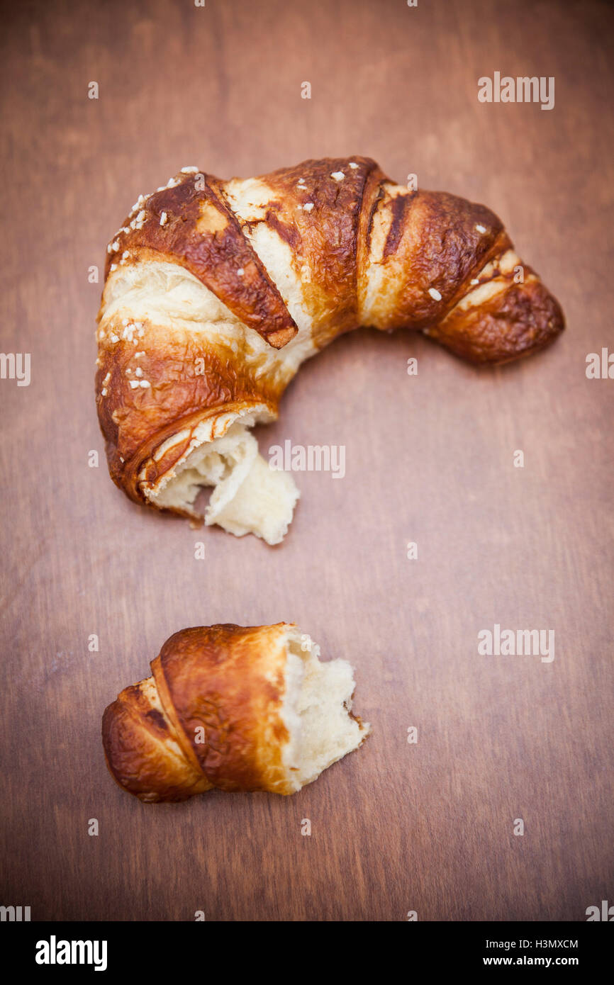 Broken croissant on wooden table Stock Photo - Alamy