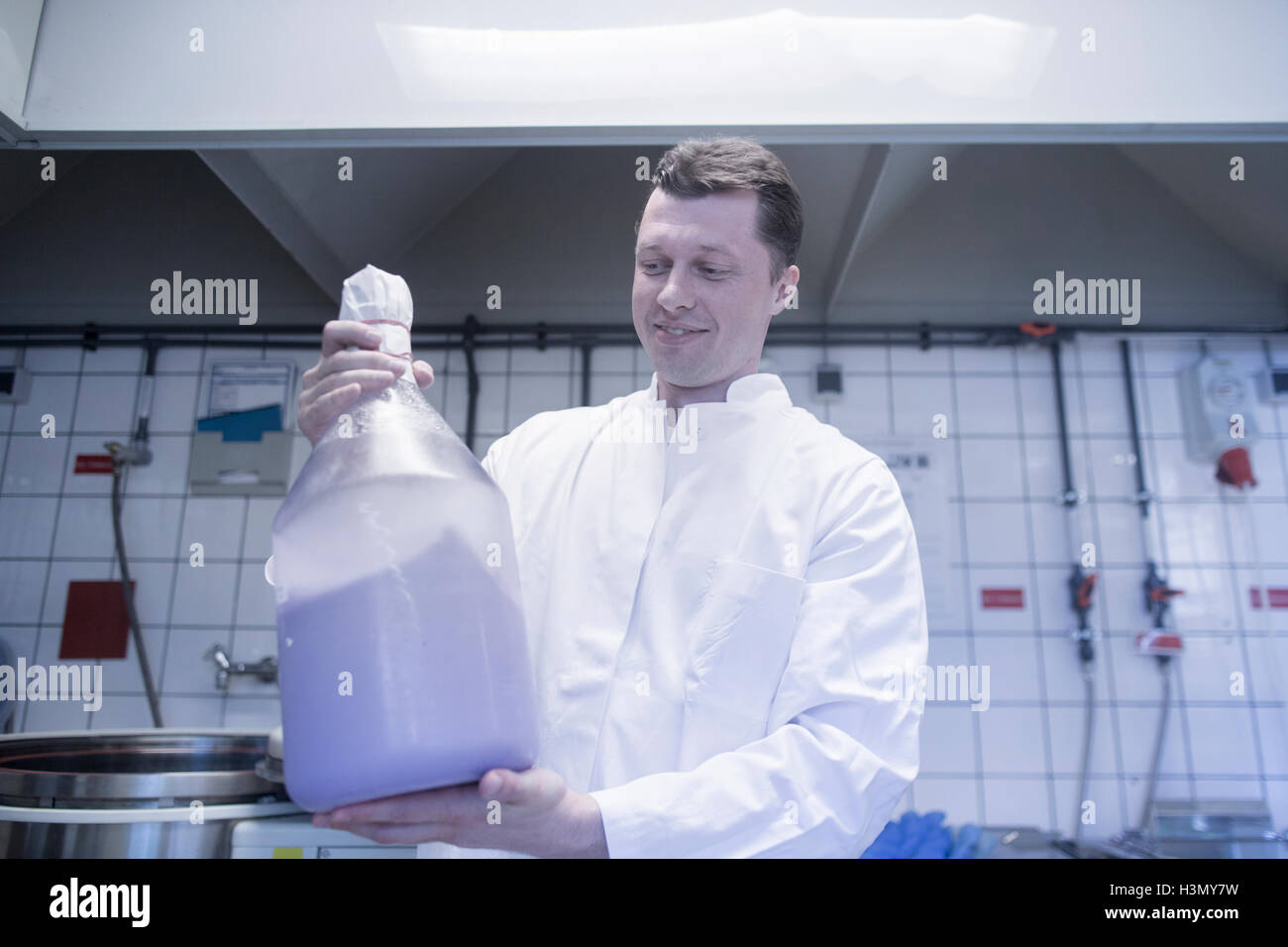 Scientist carrying large bottle of chemical in laboratory Stock Photo ...