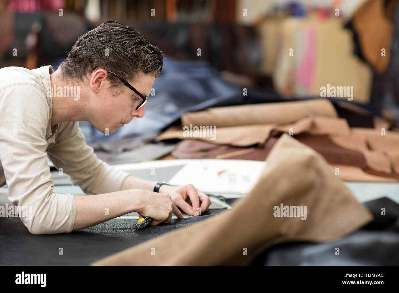 Man cutting leather with utility knife in leather jacket manufacturers ...