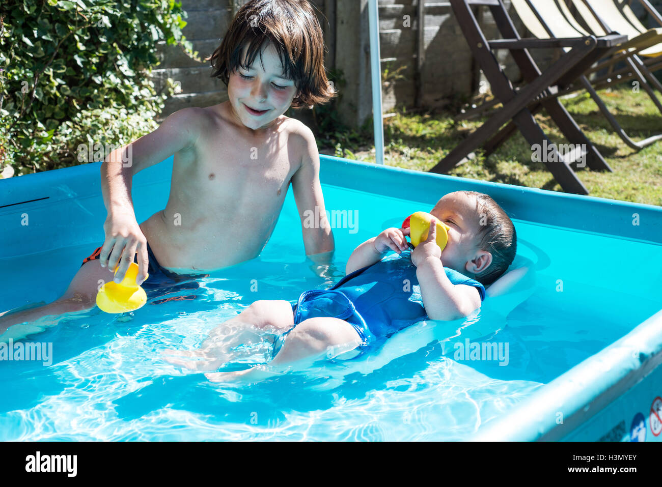 Happy brothers playing in inflatable pool on summer day Stock Photo - Alamy