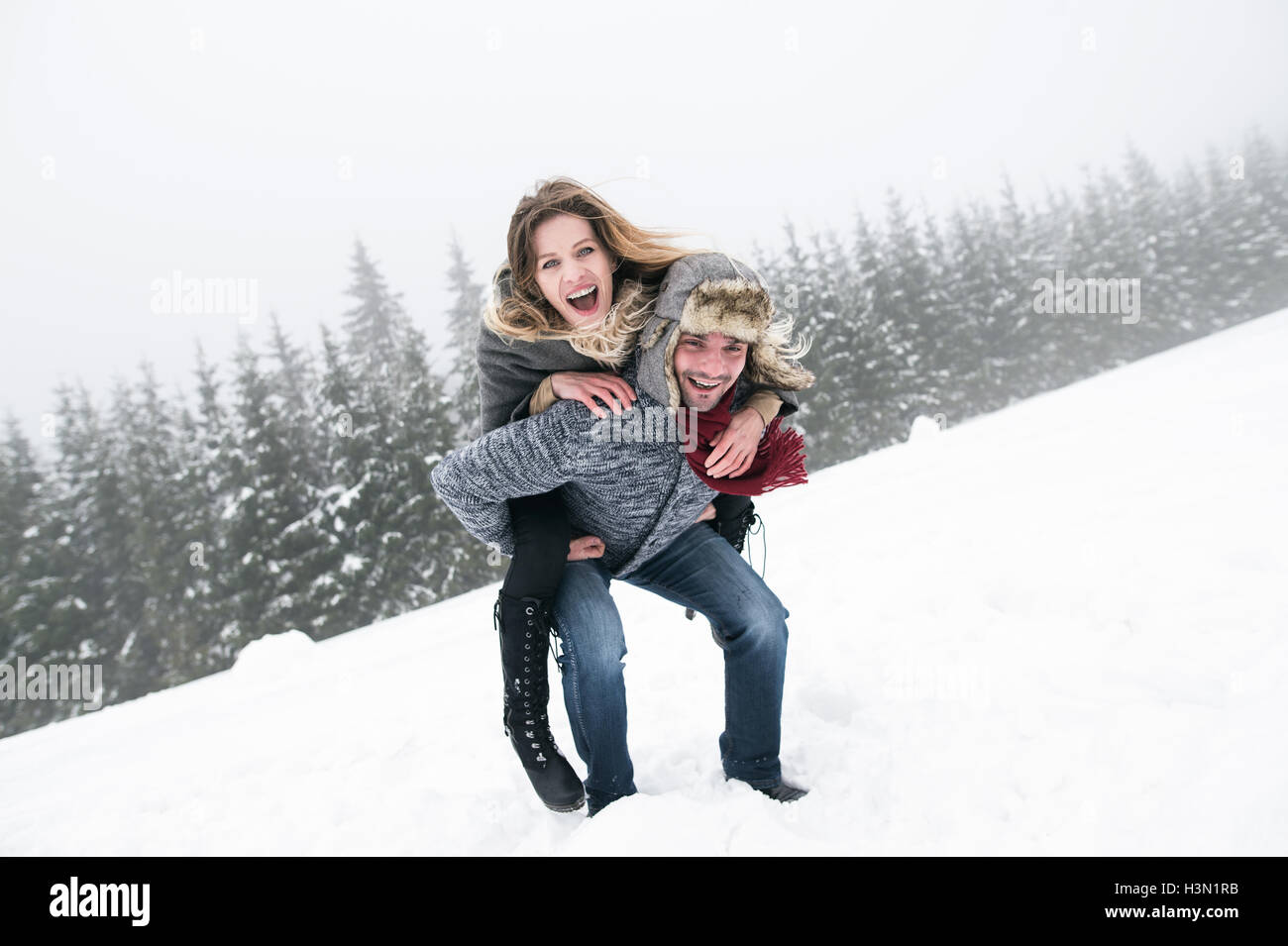 Couple in love, man giving woman piggyback. Winter nature Stock Photo ...