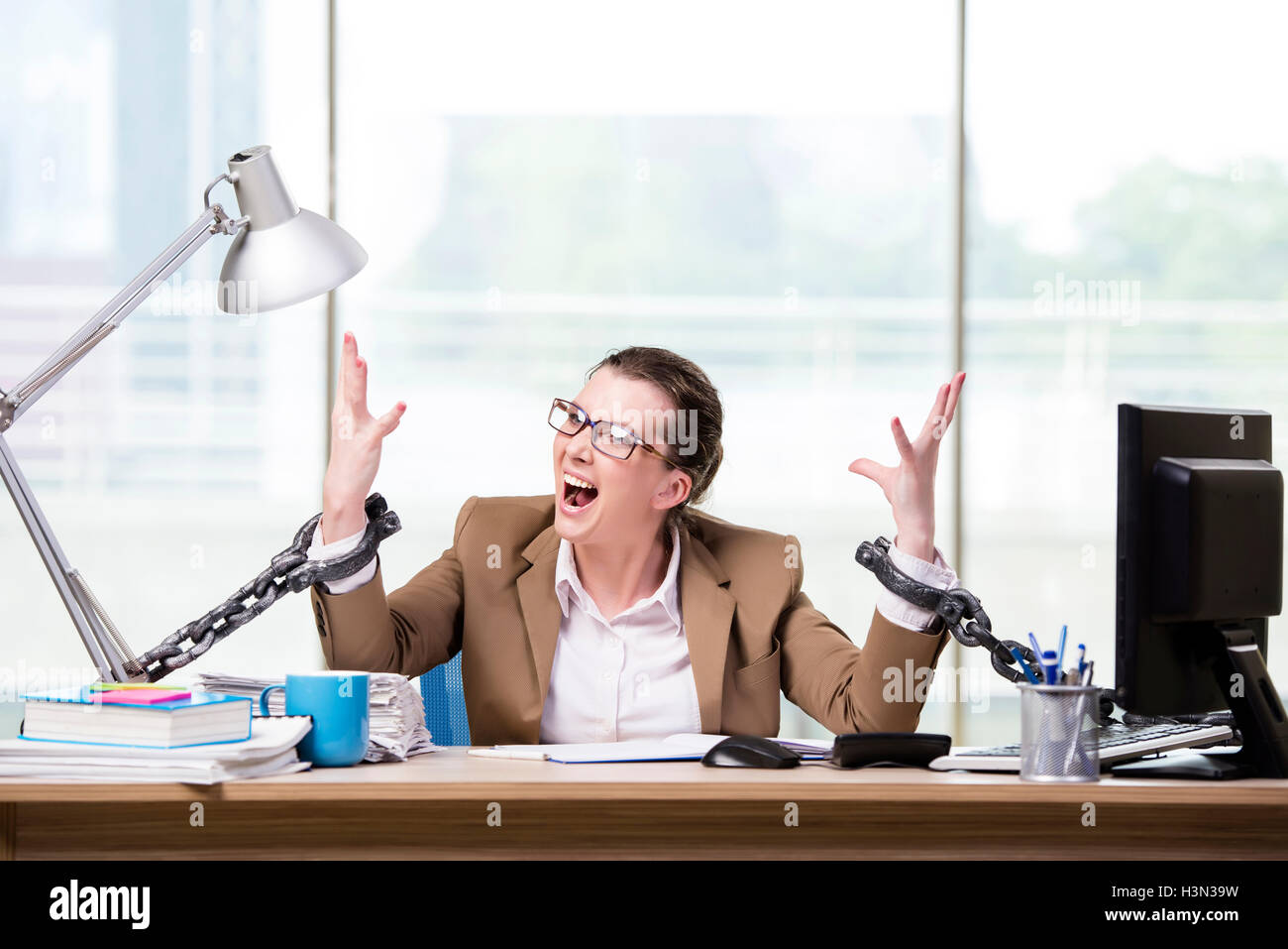 Woman chained to her working desk Stock Photo - Alamy