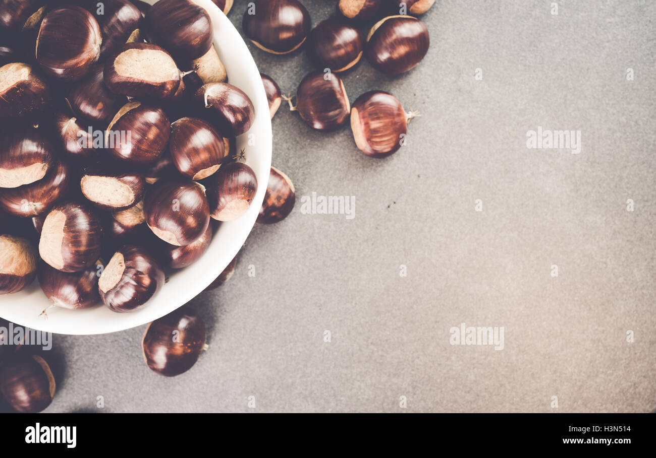 ripe chestnuts in a porcelain bowl on a stone surface - seasonal fruits ...