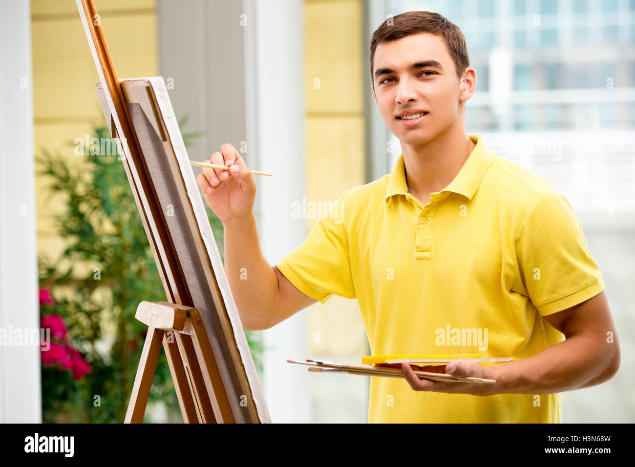 Young male artist drawing pictures in bright studio Stock Photo - Alamy