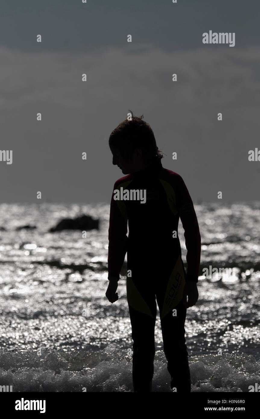 Silhouetted boy standing in the sea Stock Photo - Alamy