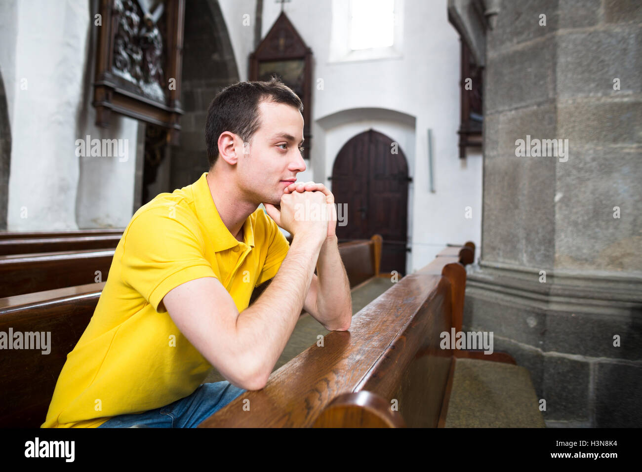 Handsome young man praying in a church Stock Photo - Alamy