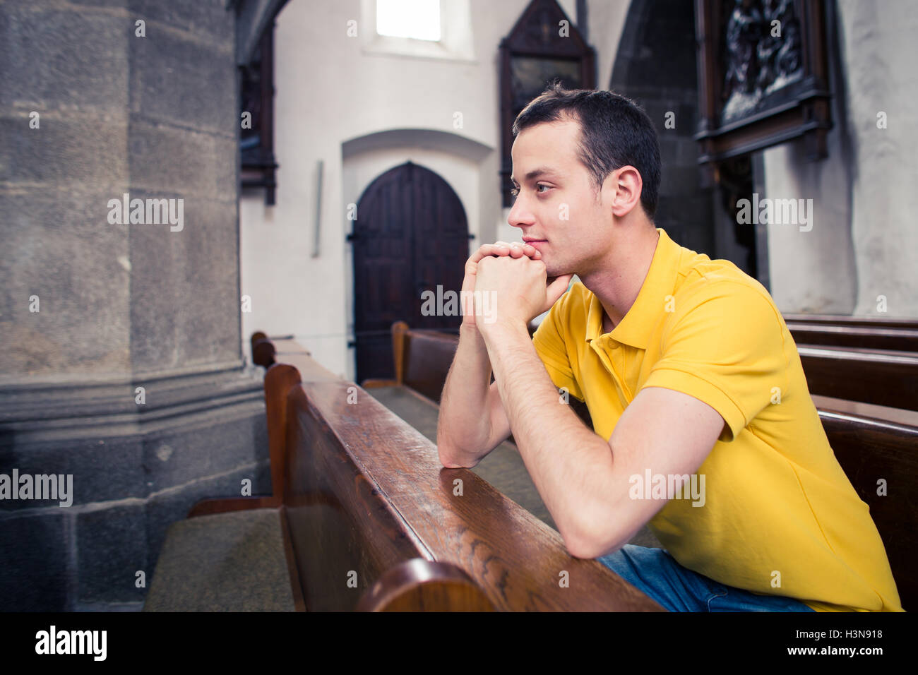 Handsome young man praying in a church Stock Photo - Alamy