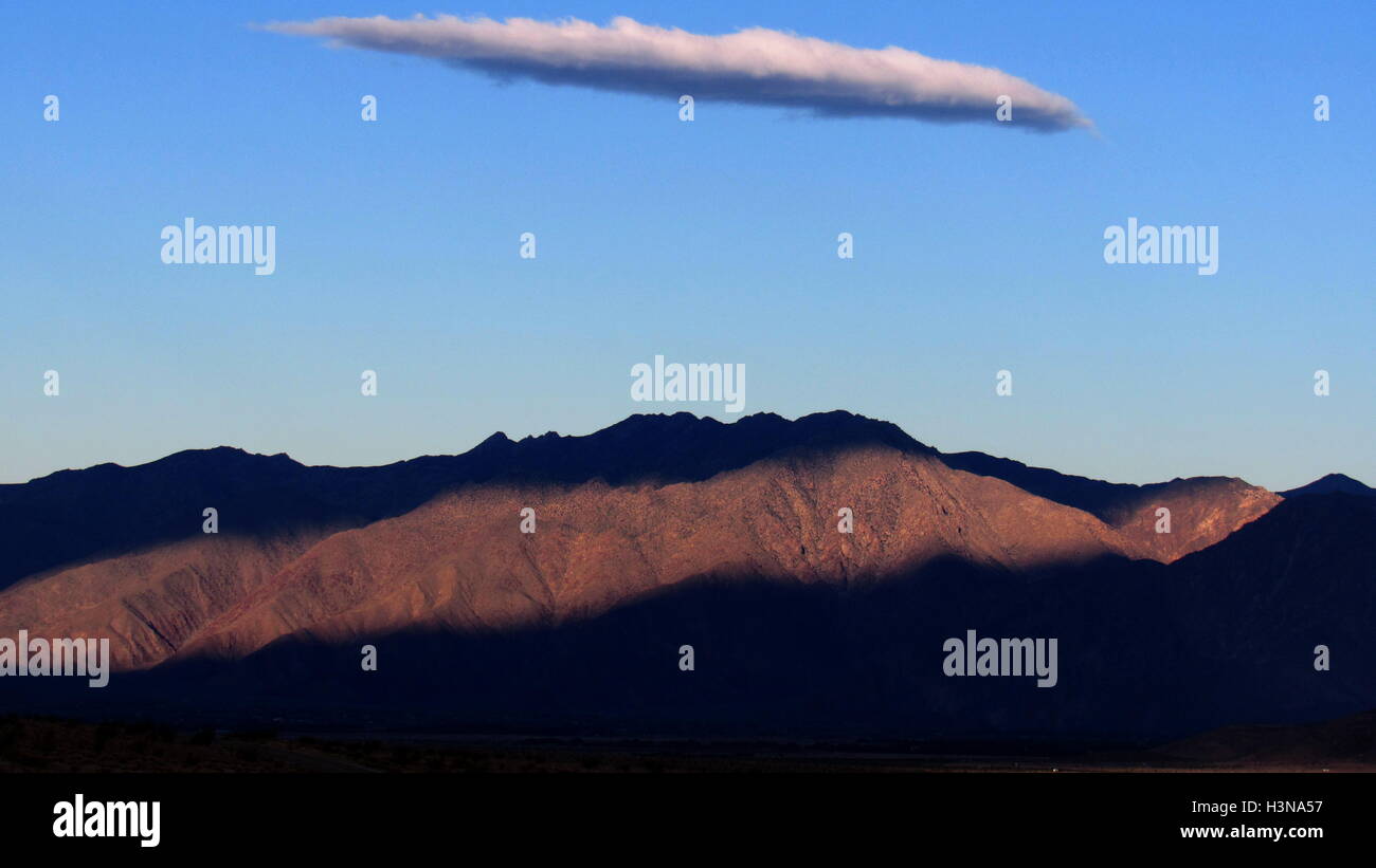 Single lone desert cloud in blue sky over the mountains that are ...
