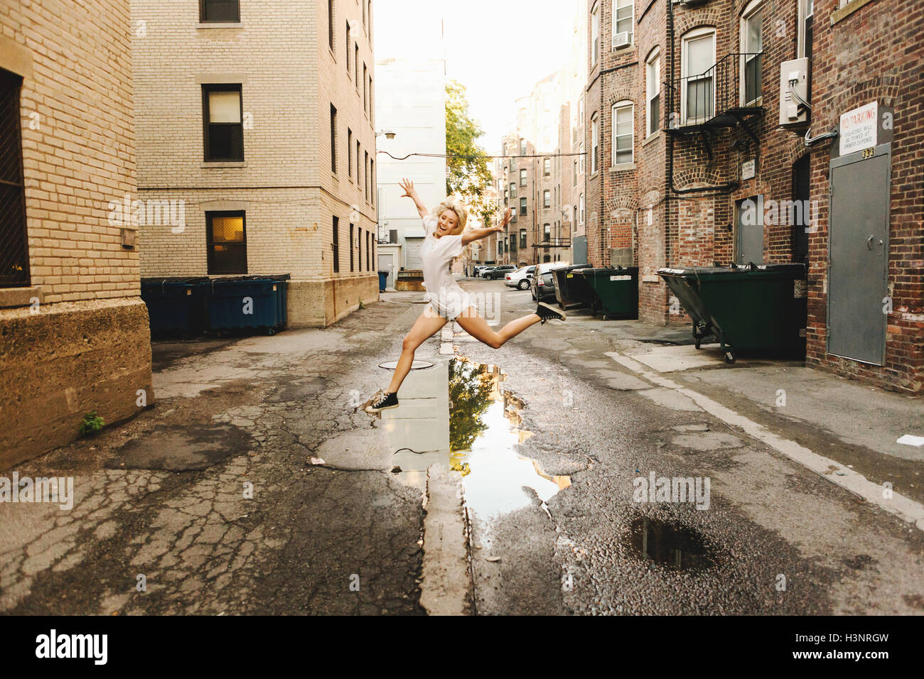 Woman jumping over puddle on road, Boston, MA, USA Stock Photo - Alamy