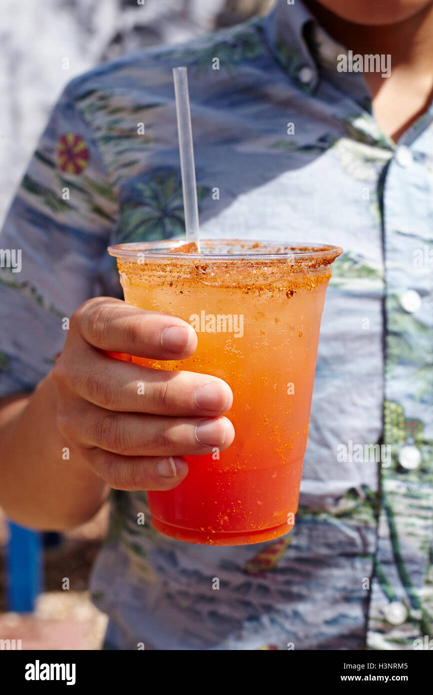 Young man holding michelada cocktail, mid section, close-up Stock Photo ...