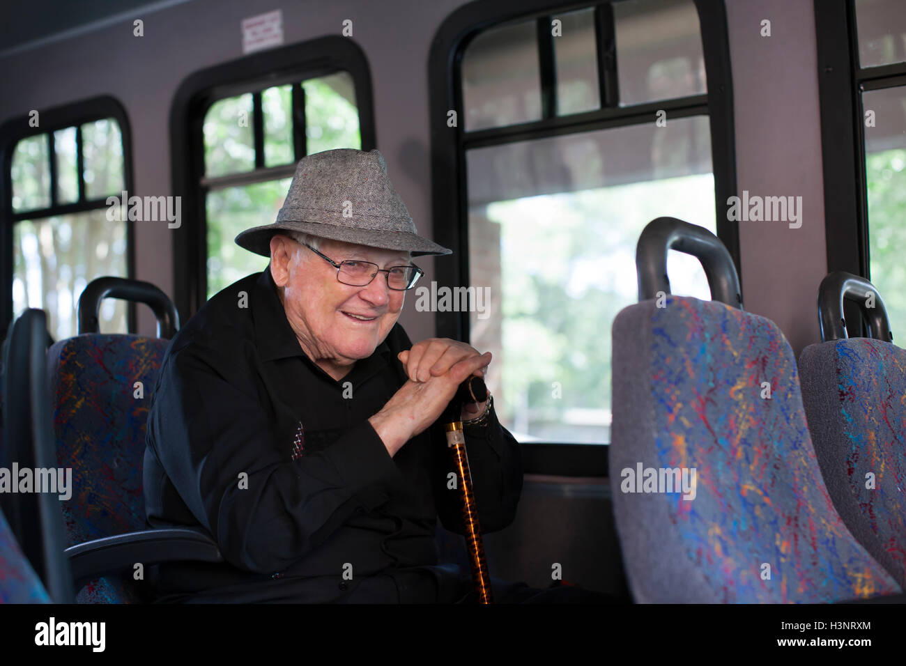 Portrait of senior man sitting on train, holding walking stick Stock ...
