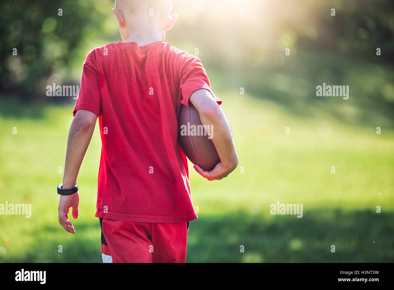 Rear view of boy holding American football Stock Photo - Alamy