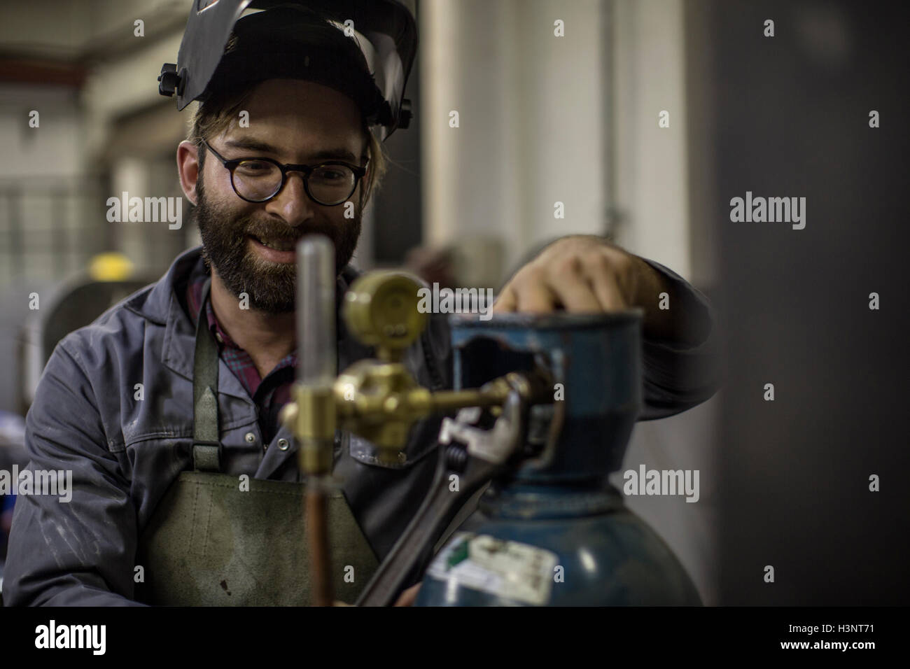 Welder looking at gas canister smiling Stock Photo - Alamy