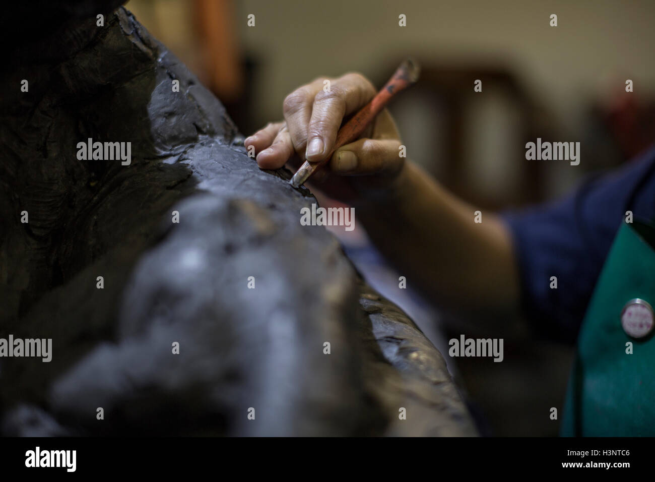 Cropped view of sculptor in artists' studio creating sculpture with ...