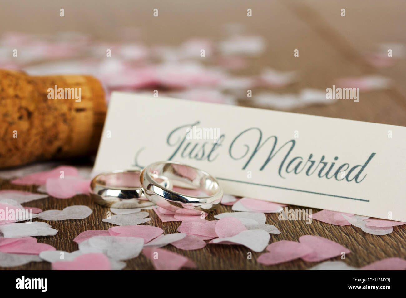 pair of white gold wedding rings on a wooden background with confetti ...