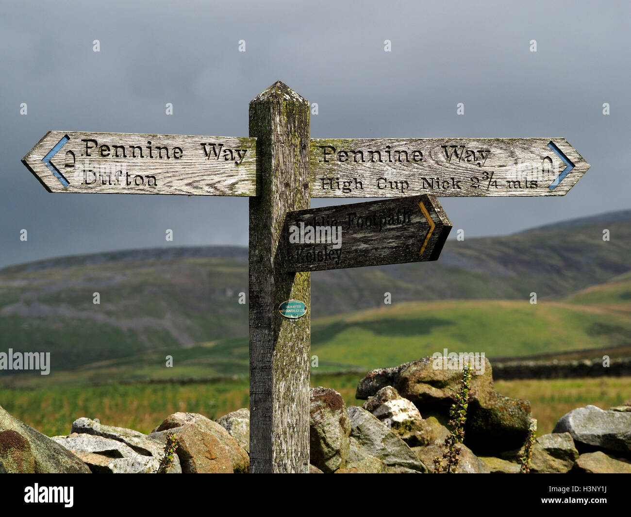 weathered colour-coded wooden fingerpost sign stone wall & moorland ...
