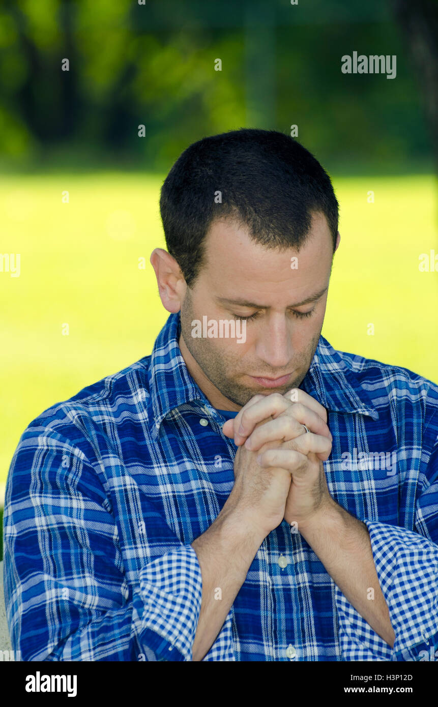 Man praying outdoors with a bright yellow and green sunlight background ...