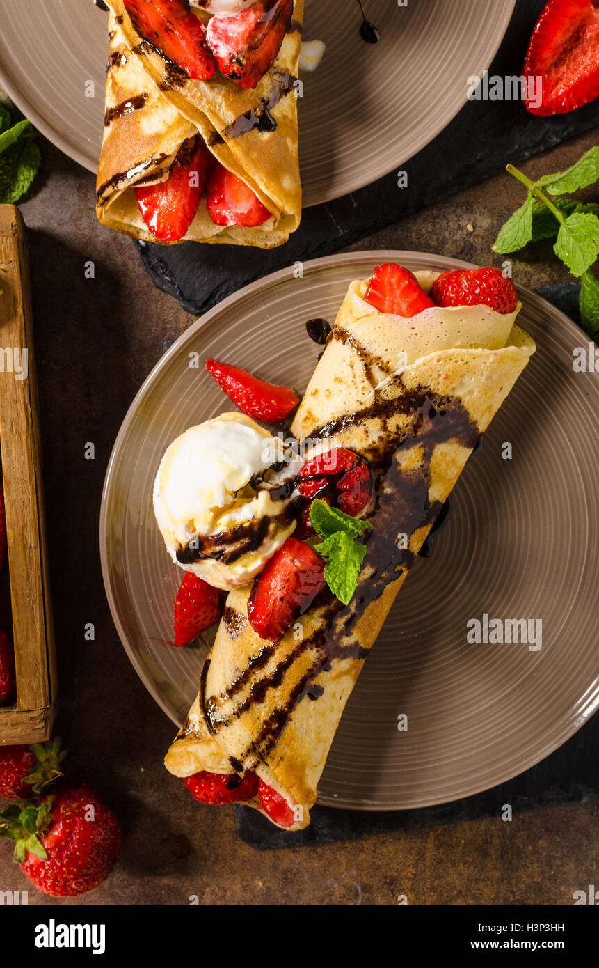 Crepes with ice cream, caramel topping and strawberries. Delicious ...