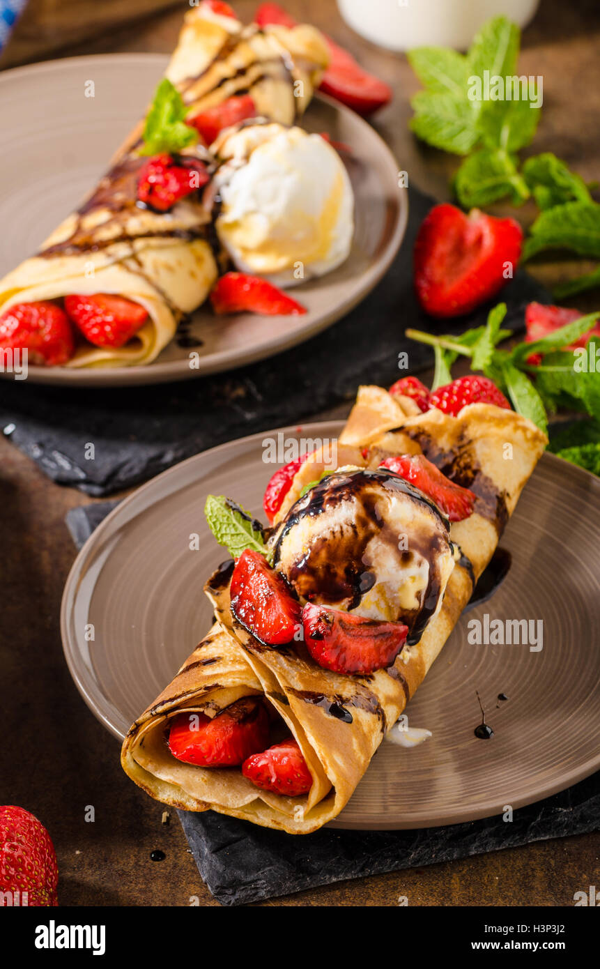 Crepes with ice cream, caramel topping and strawberries. Delicious ...