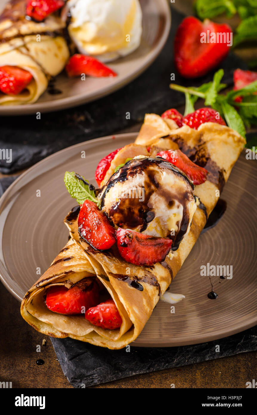 Crepes with ice cream, caramel topping and strawberries. Delicious ...