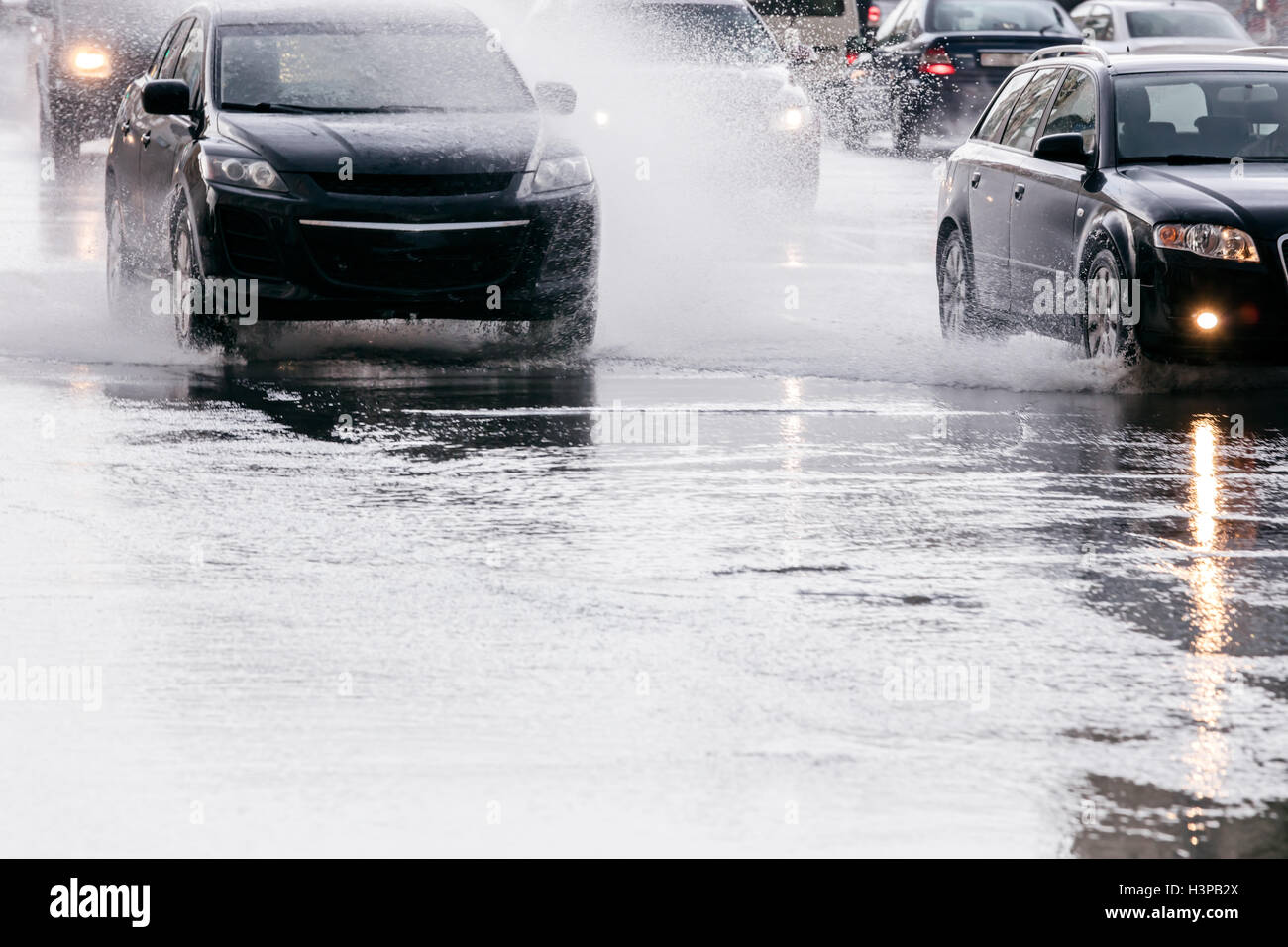 city road during heavy rain. car traffic driving on flooded street ...